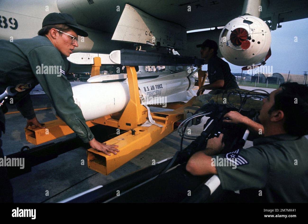 A ground crew loads a Maverick missile on the wing pylon of an A-10 ...