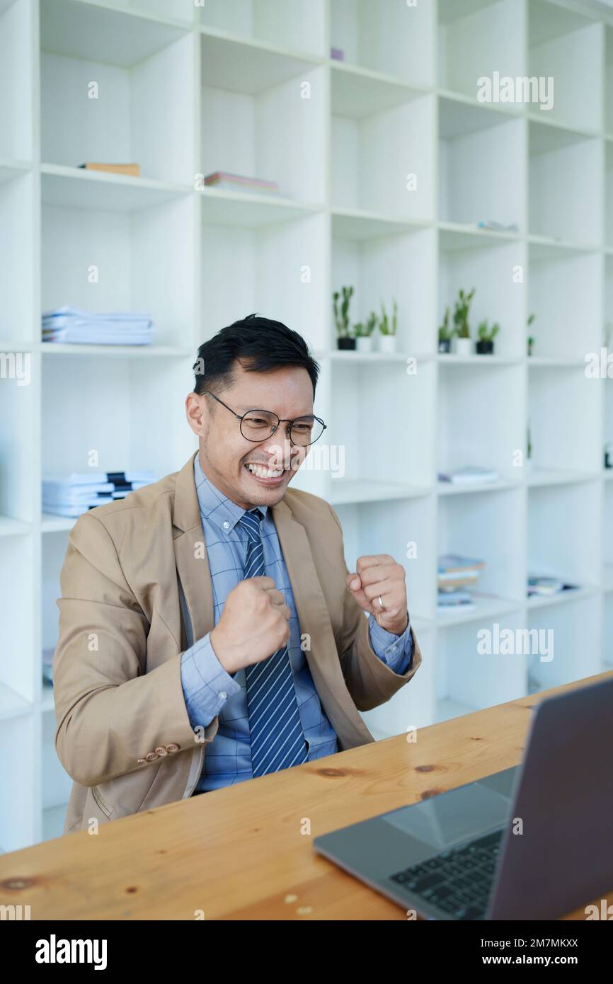 Portrait of an Asian male business owner standing with a computer ...