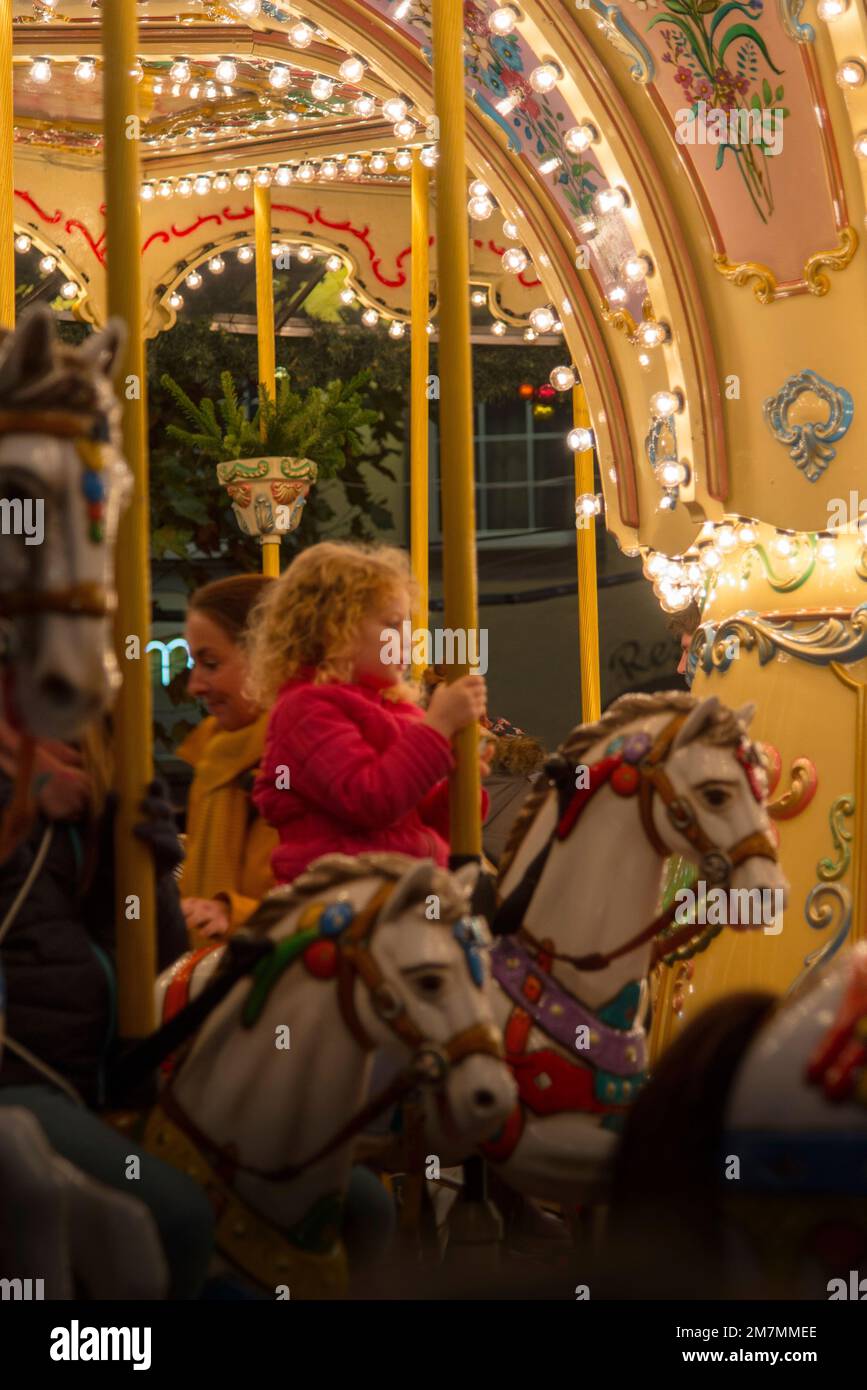 Little blonde girl sitting on a classic carousel Stock Photo - Alamy