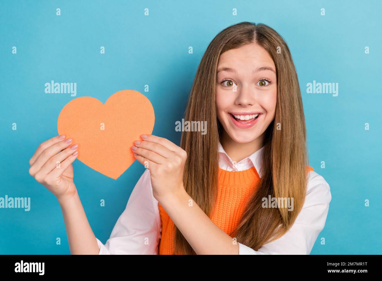 Portrait of sweet excited girl toothy smile hands hold orange paper ...