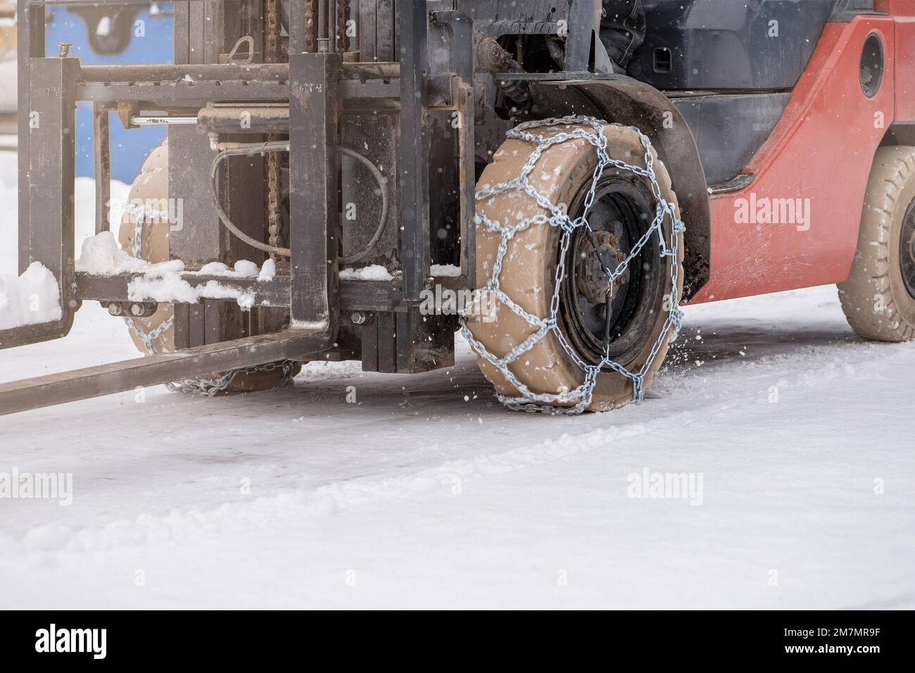 Tractor wheel with chain. Tractor or loader on a slippery snowy road ...