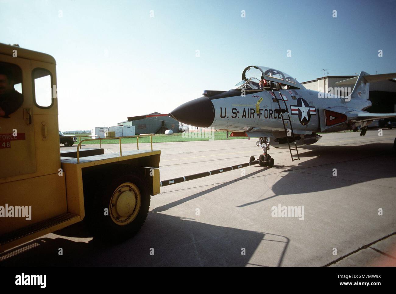 A vehicle tows an F-101 Voodoo aircraft from a hangar. The aircraft is ...