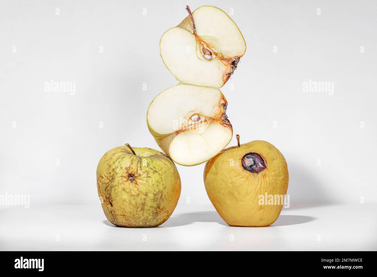 Spoiled, dehydrated and rotten apples, one apple cut in half, two apple halves, fruit isolated ...