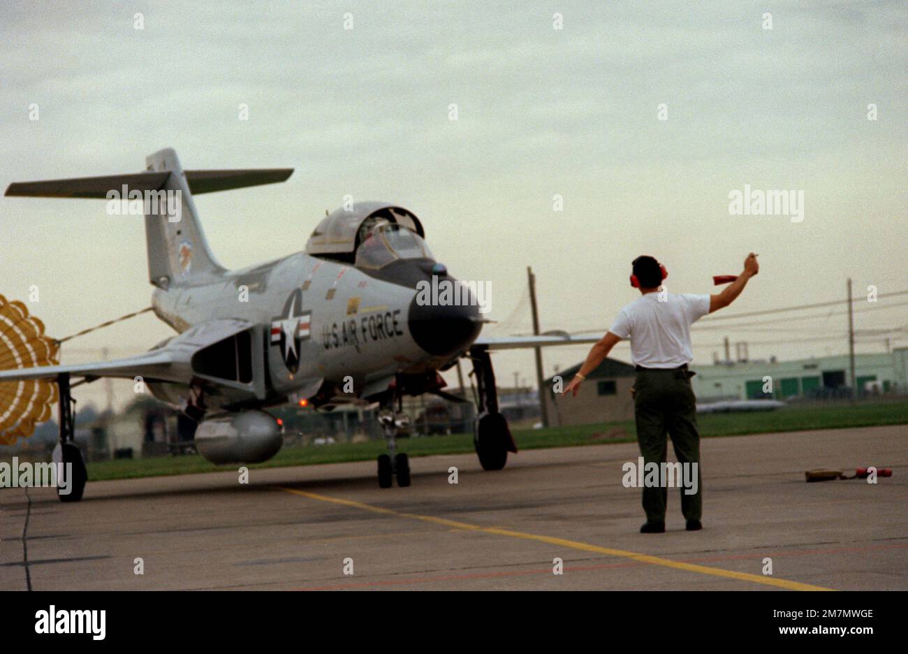 A ground crew chief marshals an F-101 Voodoo aircraft into a parking ...