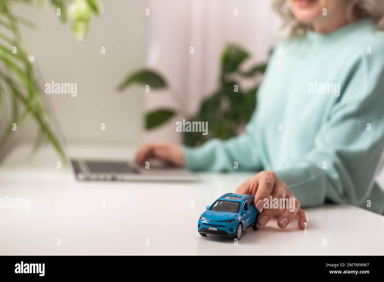 hands of a woman on a desk behind a keyboard with a small model car ...