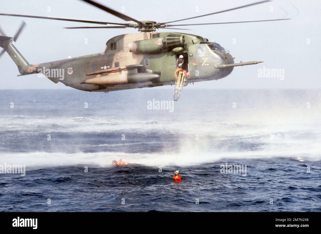 A litter is dropped from a hovering HH-53 helicopter to pararescuemen ...