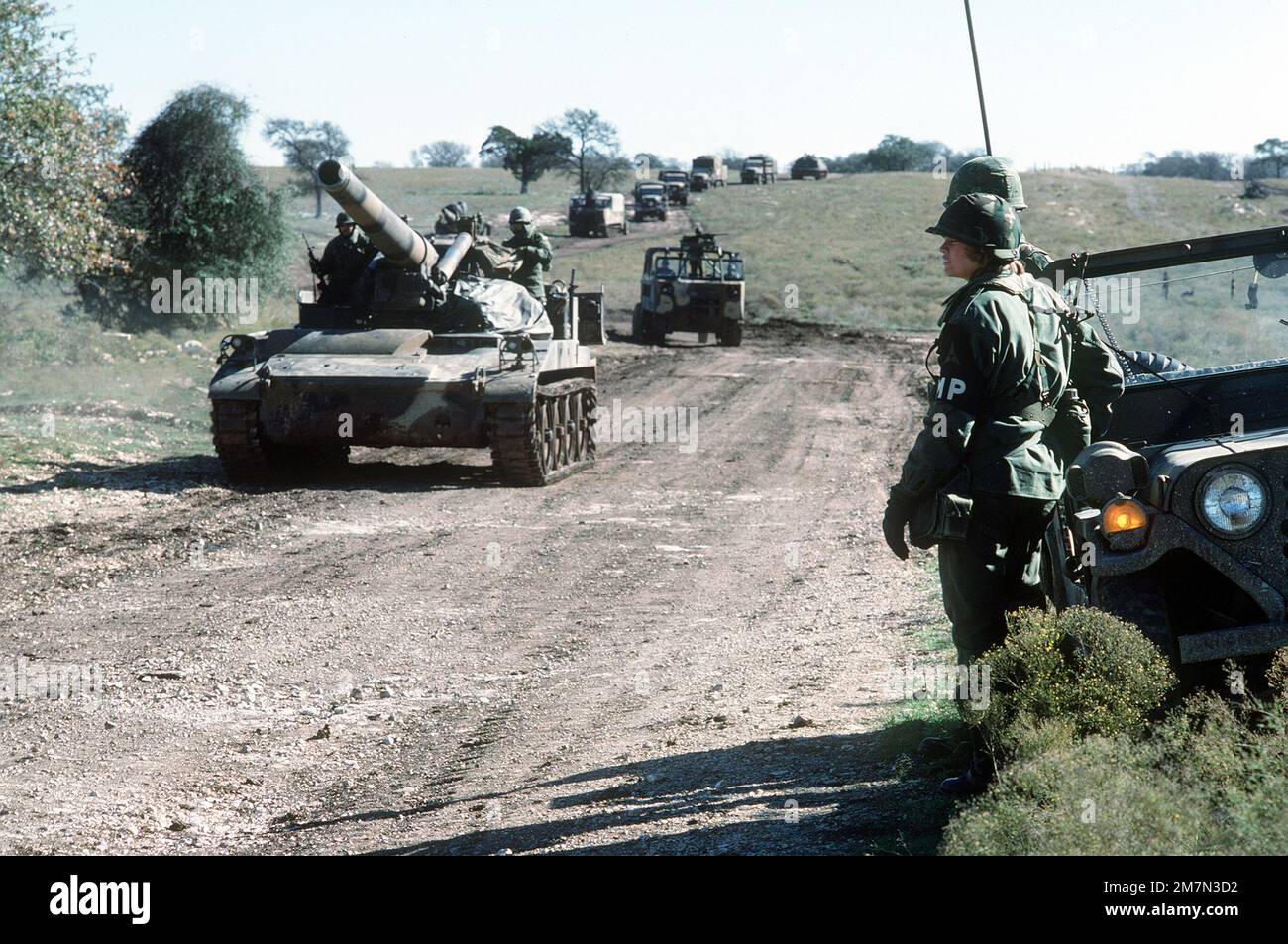 U.S. Army military policemen observe an M-110 203mm howitzer passing by ...