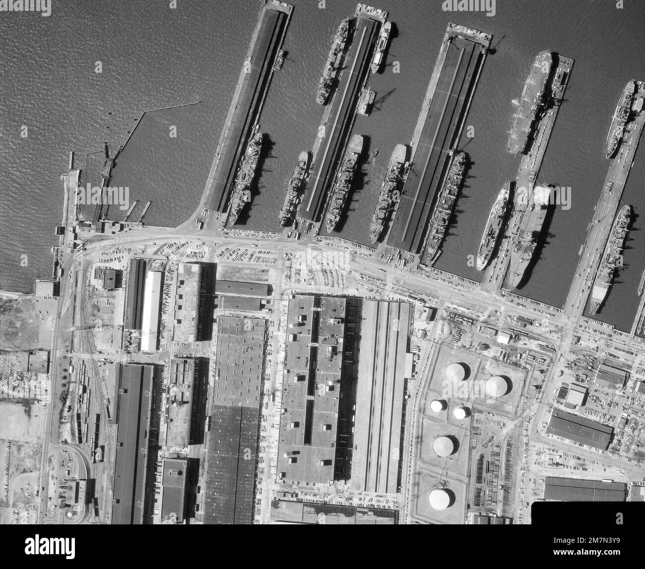 An aerial view of various US Navy ships tied up at piers beside the ...