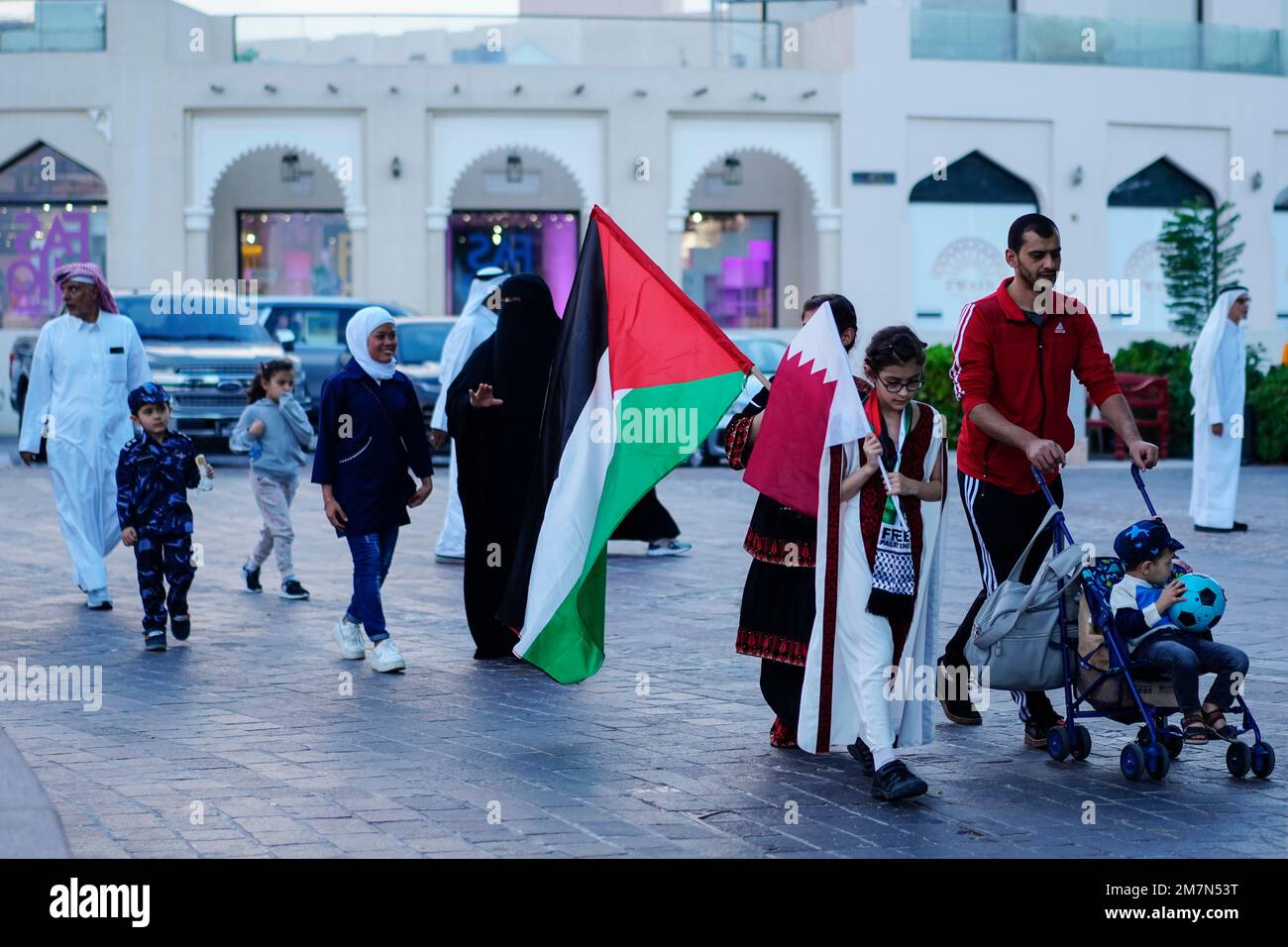 People walk with the Palestinian, centre, and Qatarian flags at Katara ...