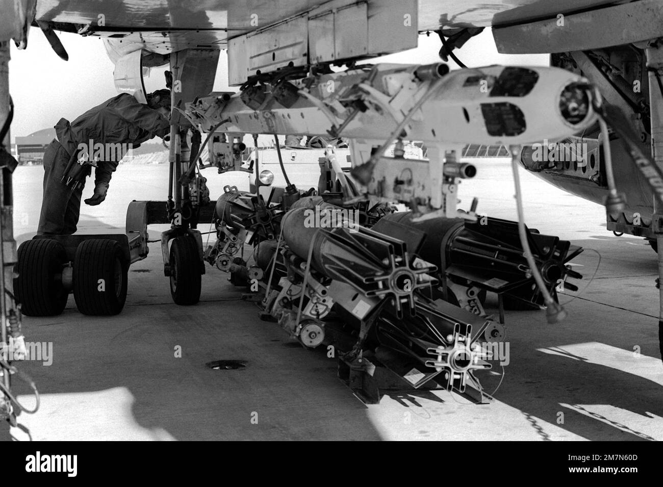 A Marine uses a crane ordnance to place the bombs on the ground under ...