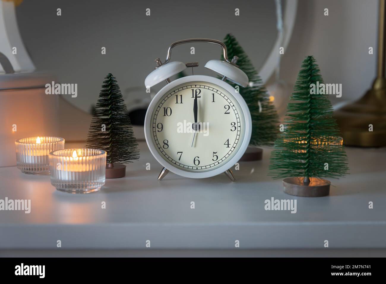 A white alarm clock, a twelve pointer, a small artificial green ...