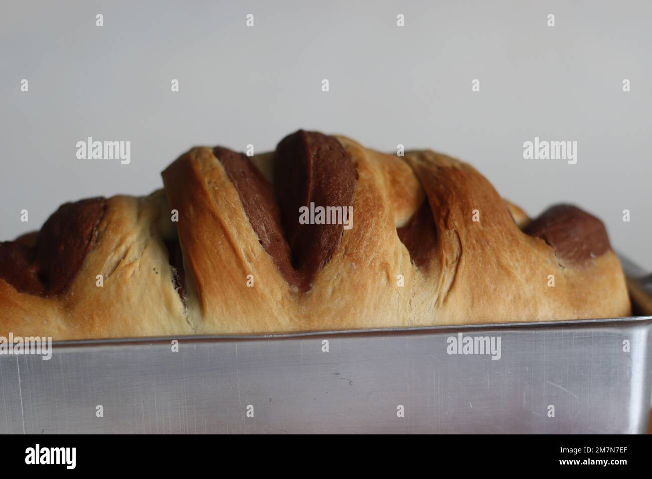 Vanilla Chocolate Swirl Bread inside loaf tin from oven. It is a ...