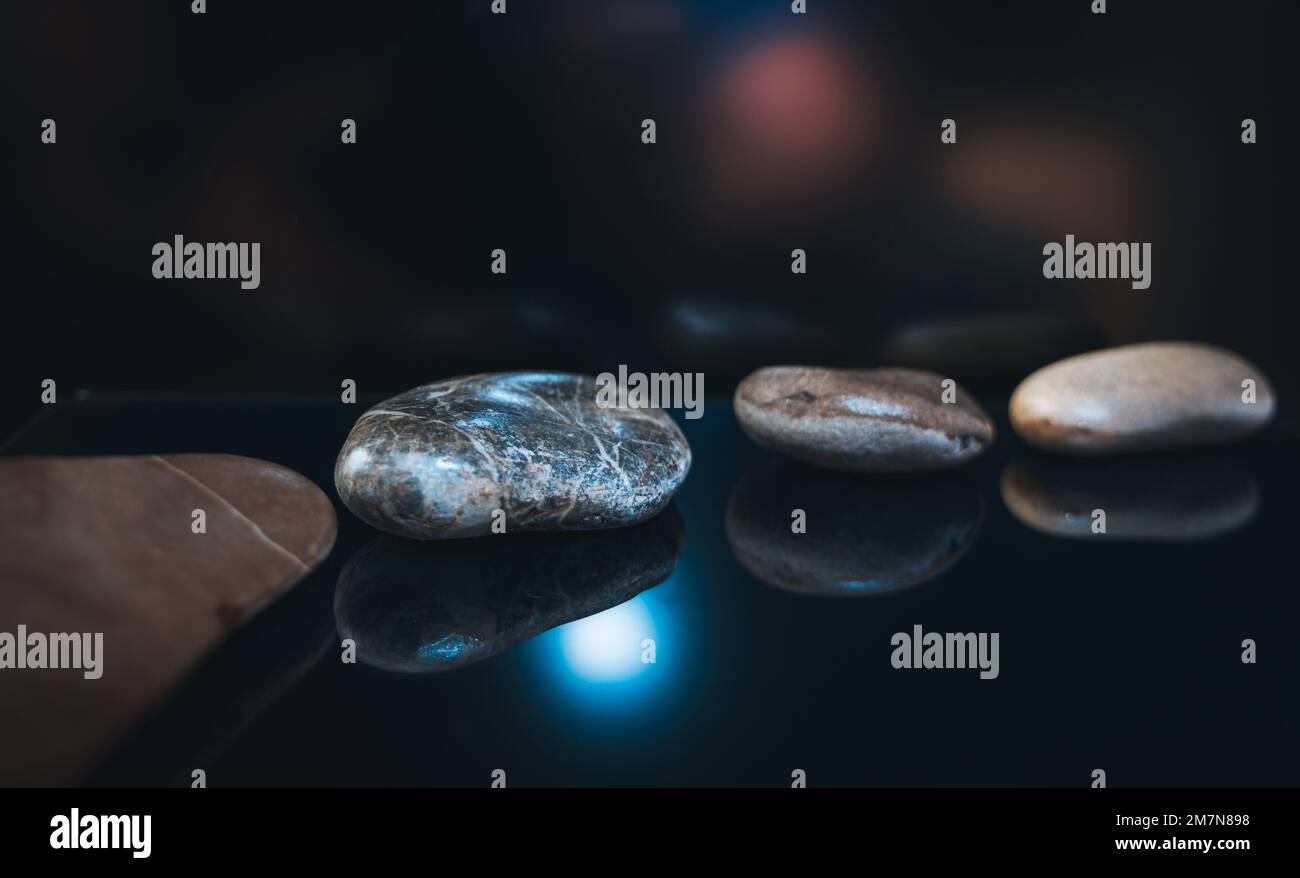A line of pebbles on a dark glowing surface Stock Photo - Alamy