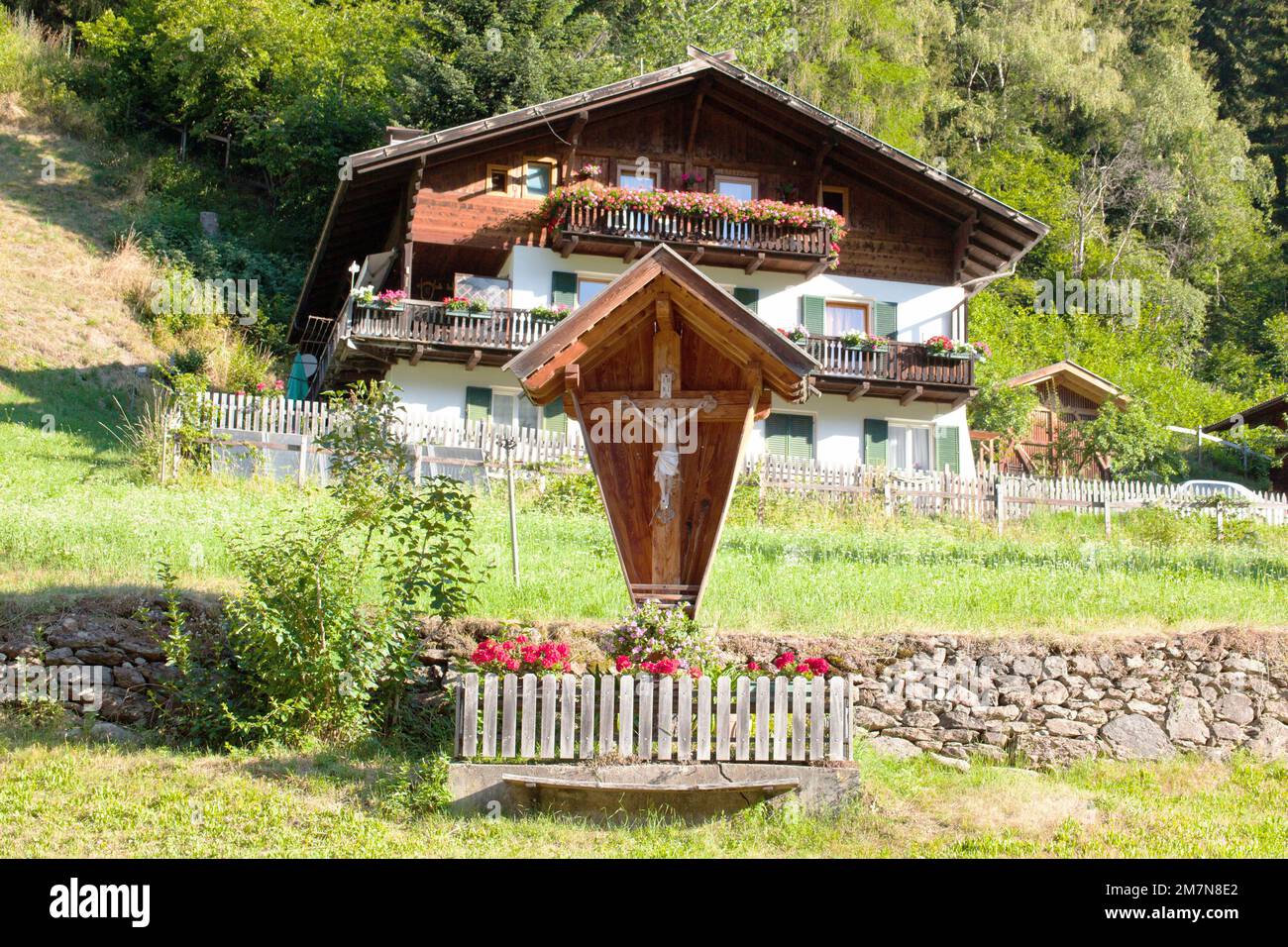 Marterl in front of South Tyrolean farmhouse on steep slope at the edge ...