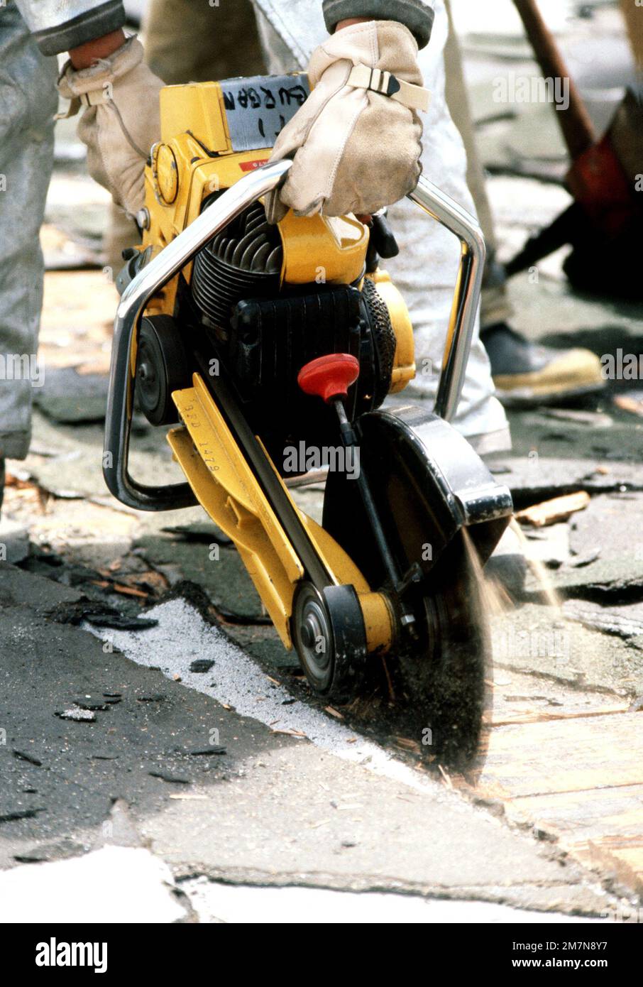 A firefighter uses a gas-powered saw to cut a trench in the roof of the ...