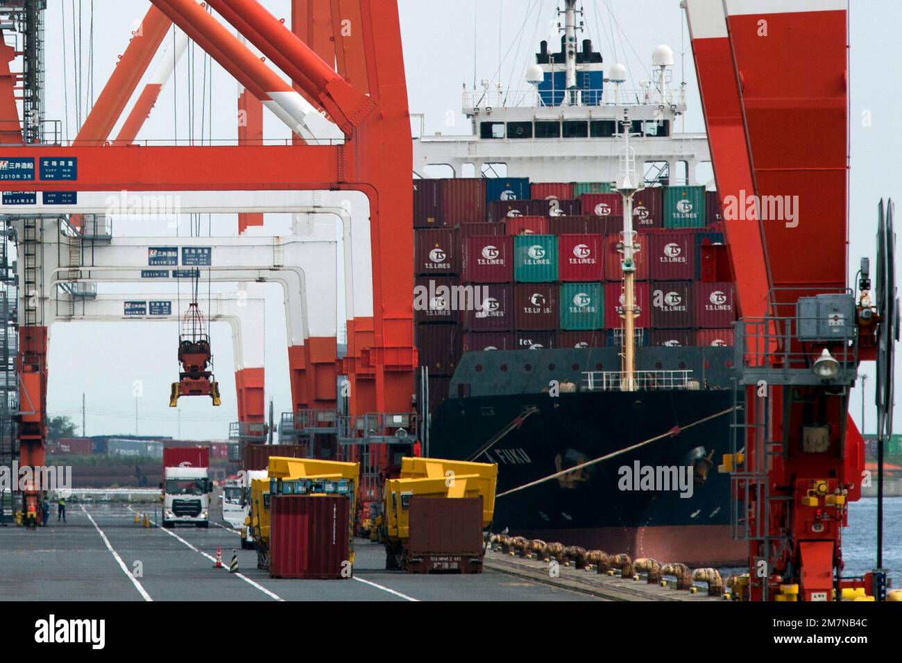FILE - A crane prepares to unload a container from a semi-trailer truck ...