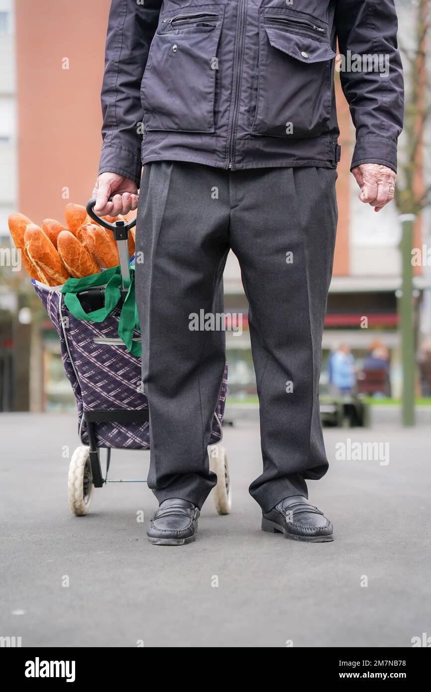 elderly gentleman standing with a shopping cart full of bread in the ...