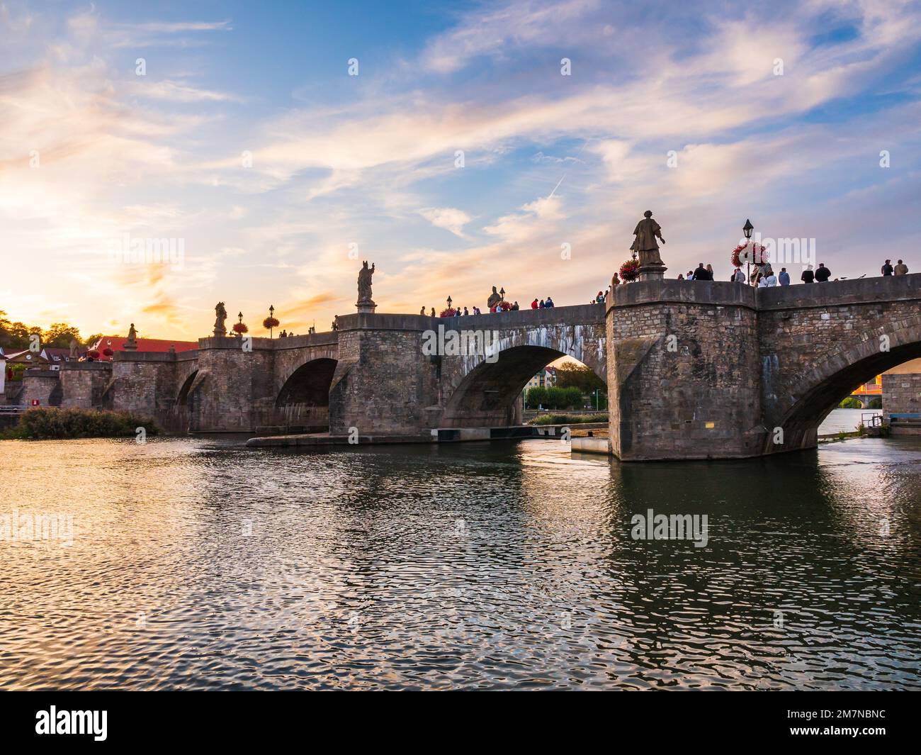 An image of an Old Main Bridge on the river under the cloudy sunset sky ...