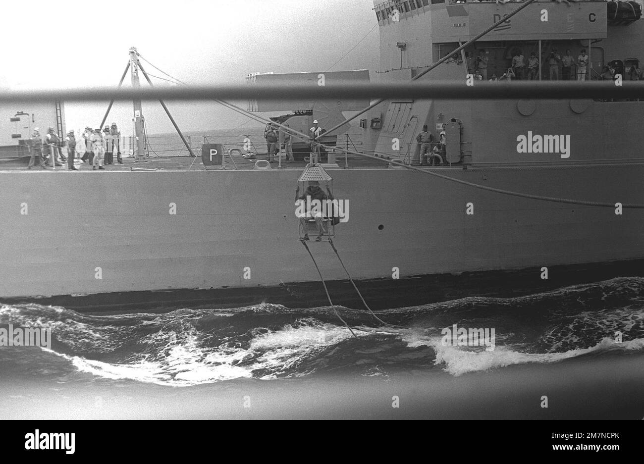 A crewman is transferred from the guided missile destroyer USS DEWEY ...