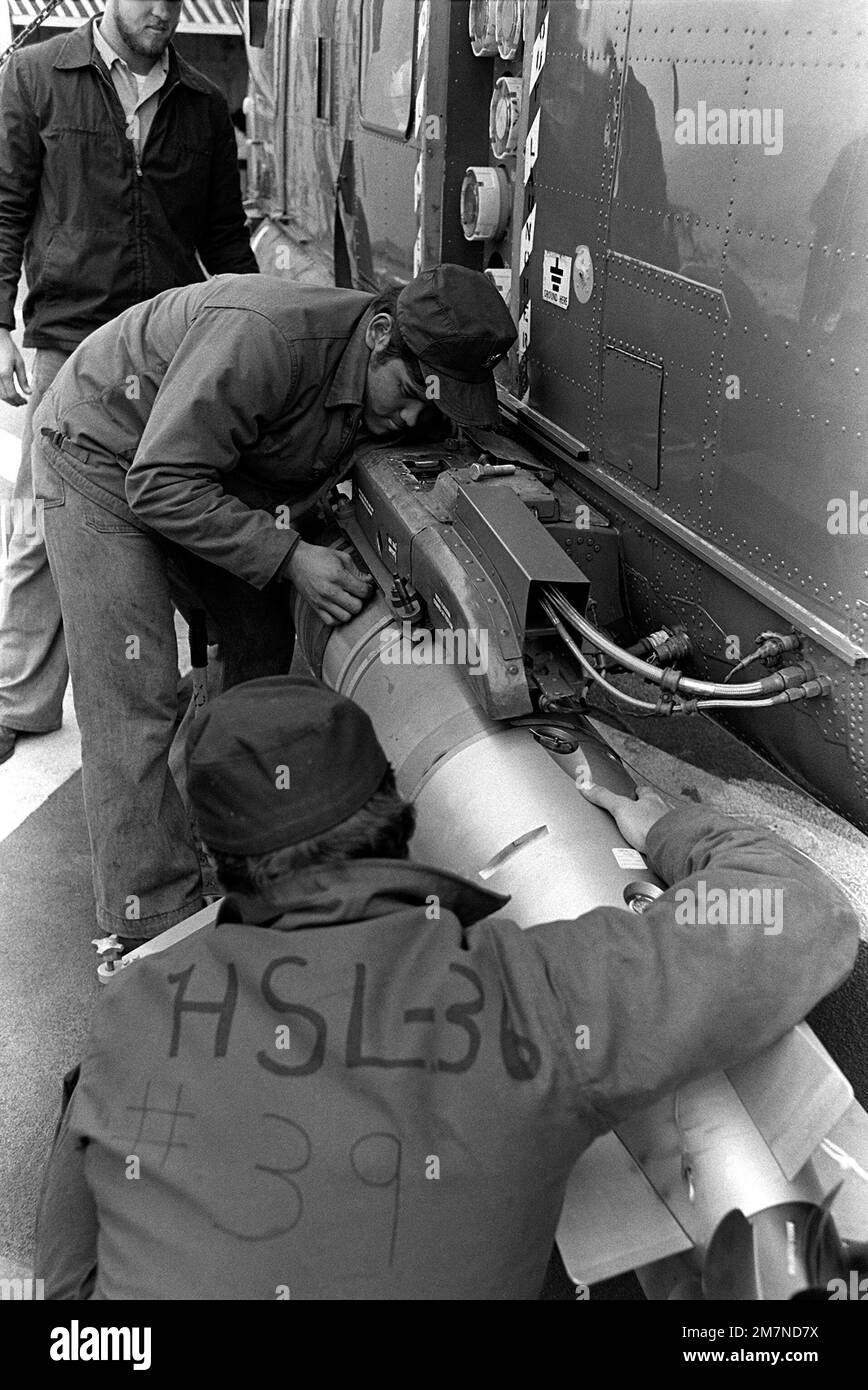 Two crewmen, aboard the frigate USS TRIPPE (FF-1075), load a Mark 46 ...