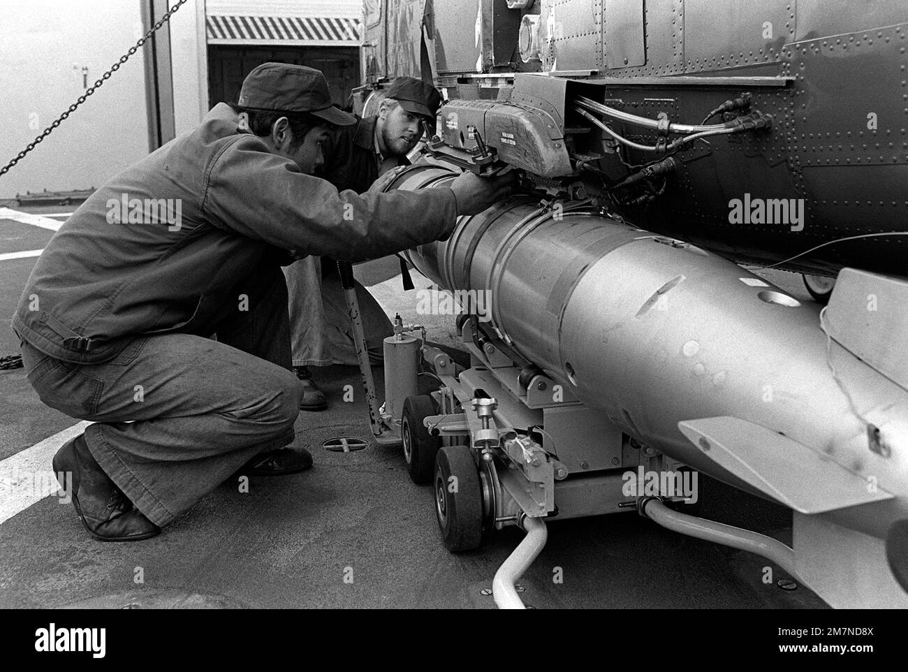 Two crewmen, aboard the frigate USS TRIPPE (FF-1075), load a Mark 46 ...