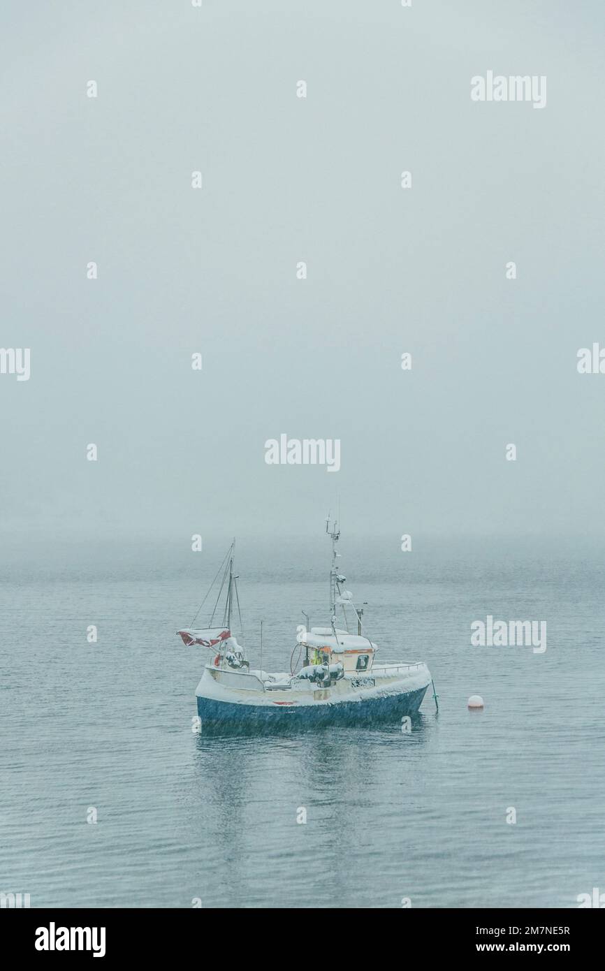 Blue fishing boat in fog, boat in fjord in Norway, snow and ice ...
