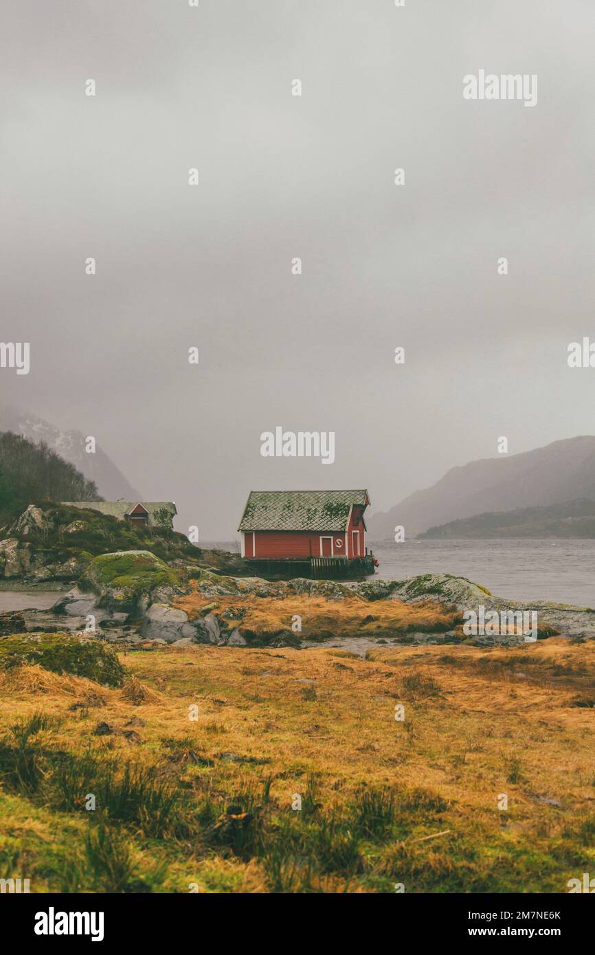 A red lonely fishing hut on the fjord in Norway, typical fjord ...