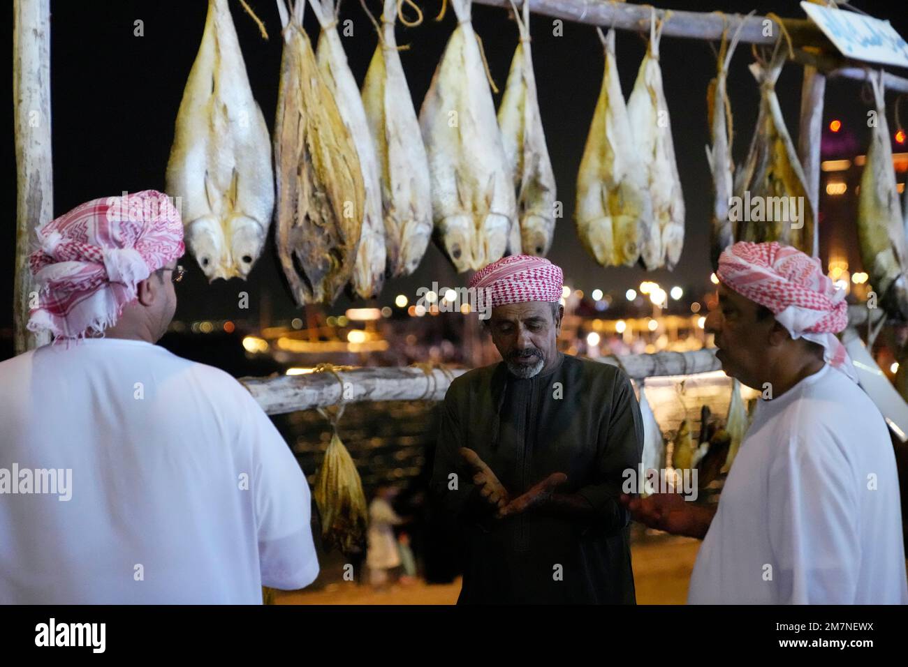 Men speak near dried salted fish at the Katara beach in Doha, Qatar ...