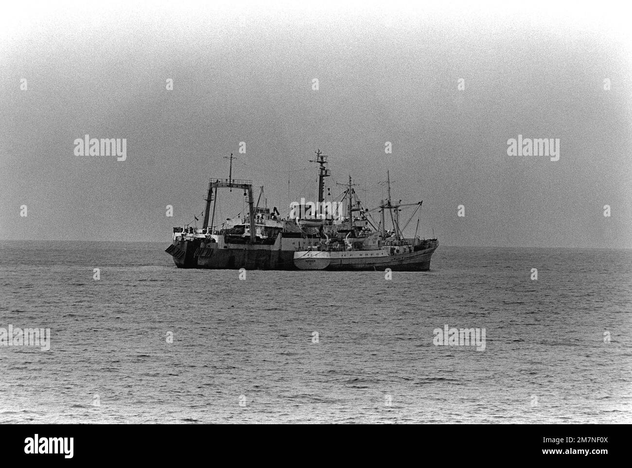 A starboard beam view of a Soviet trawler anchored offshore during ...