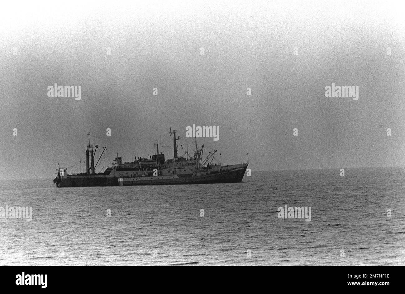 A starboard beam view of a Soviet trawler anchored offshore during ...