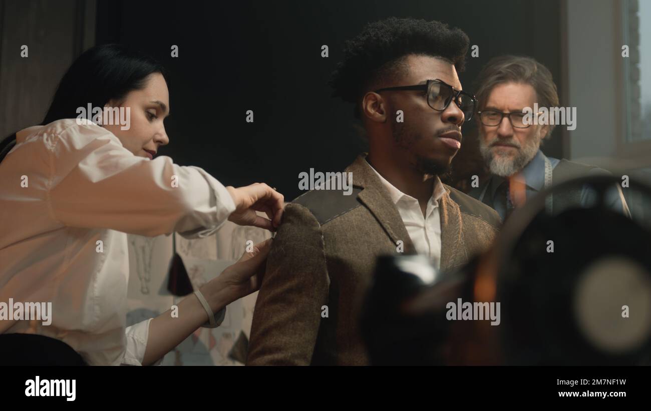 Female tailor measures tailored suit, discusses with client size and ...