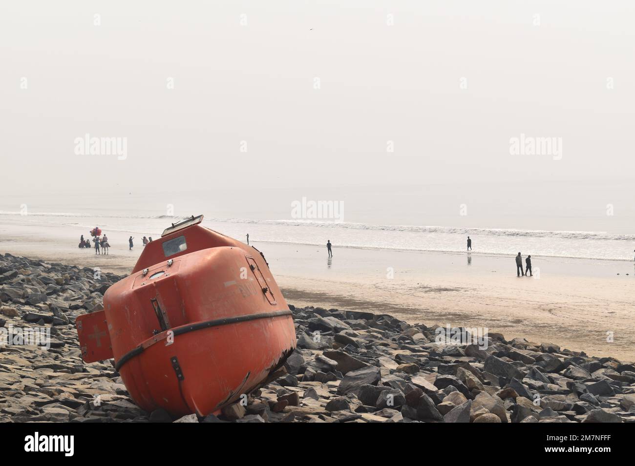A closeup shot of a marine lifeboat capsule on stones with people on ...
