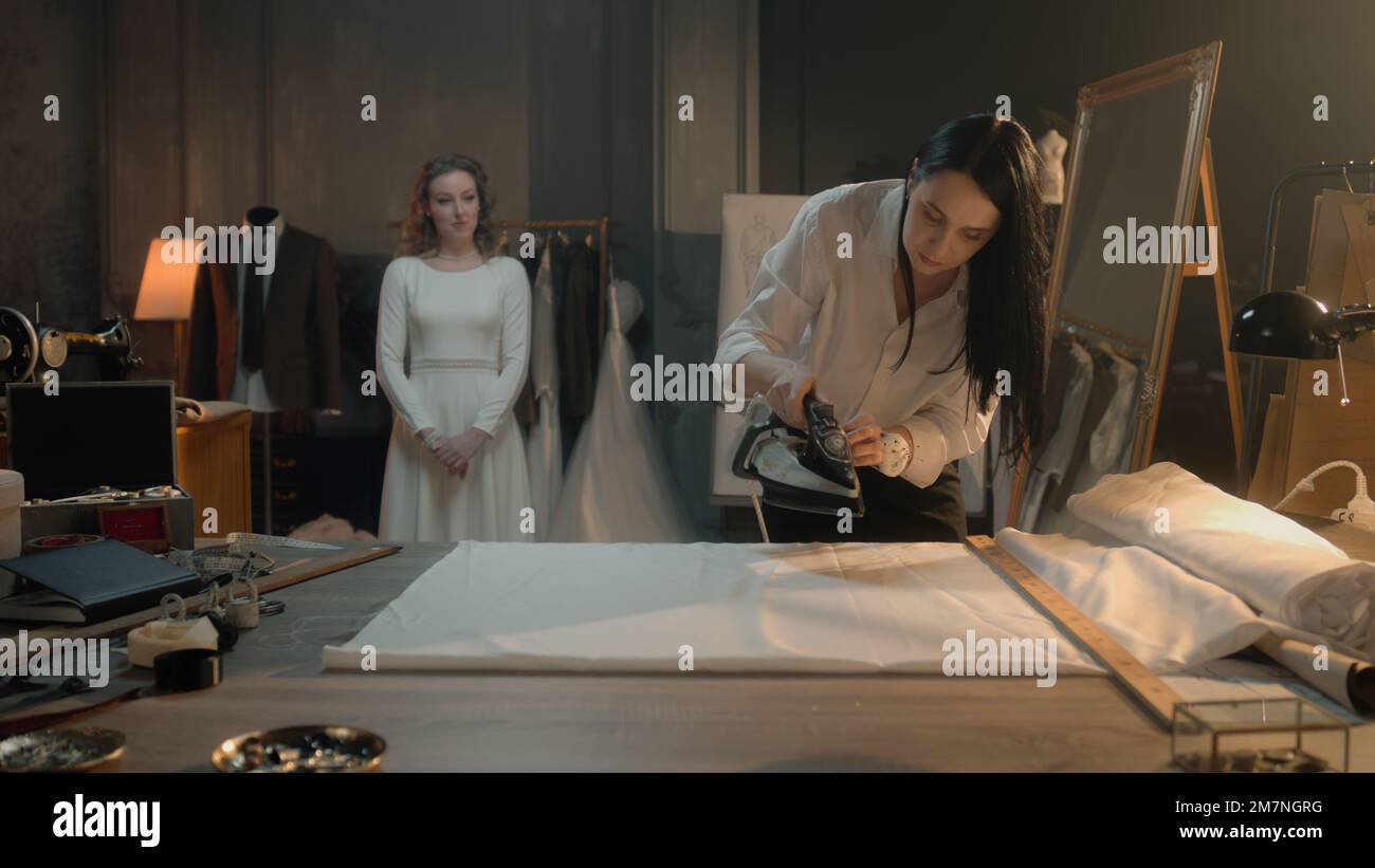 Cinematic shot of female tailor ironing fabric in stylish luxury ...