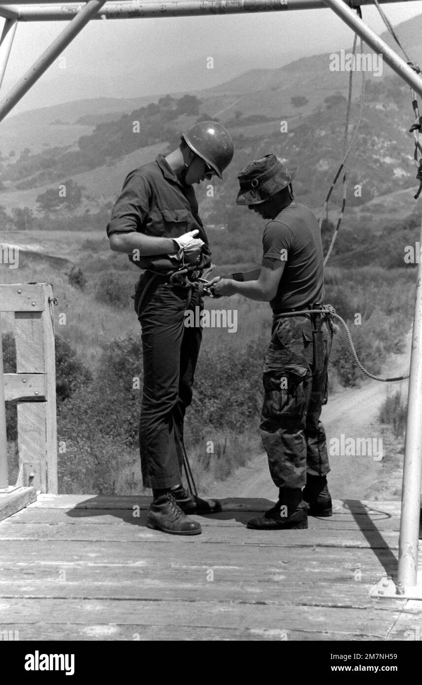 A midshipmen is instructed by a Marine instructor on how to put on a ...