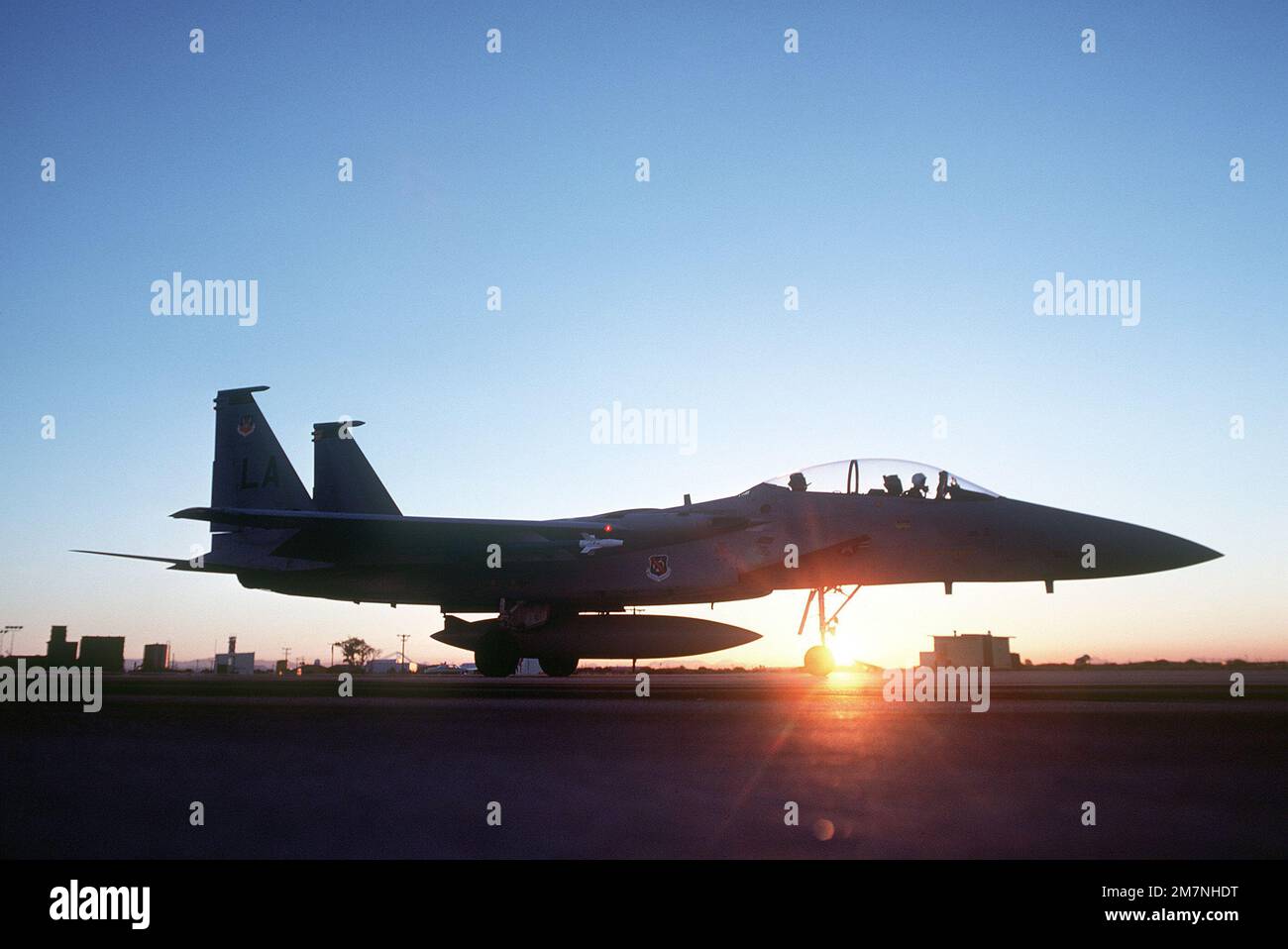 A right side view of an F-15 Eagle aircraft, silhouetted against ...