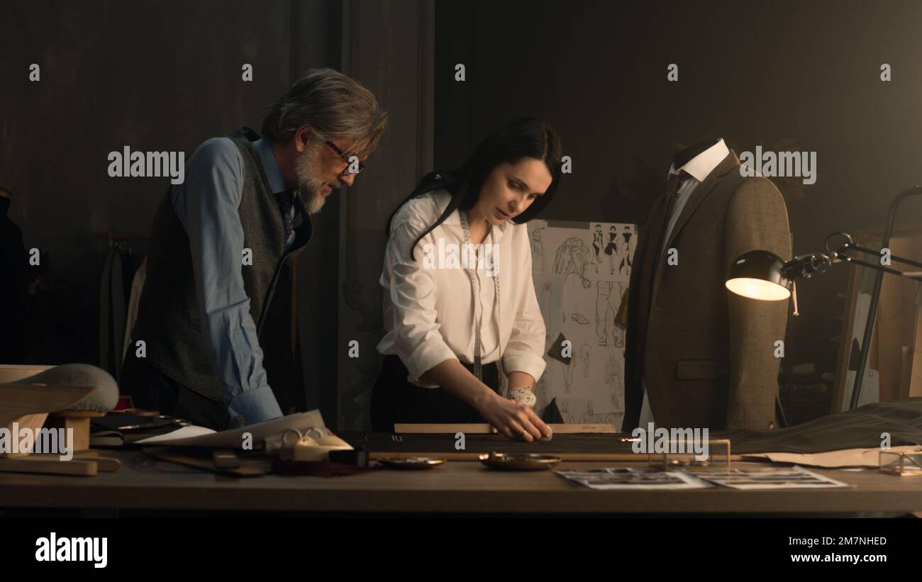 Male and female tailors working on sketch pattern of business or ...