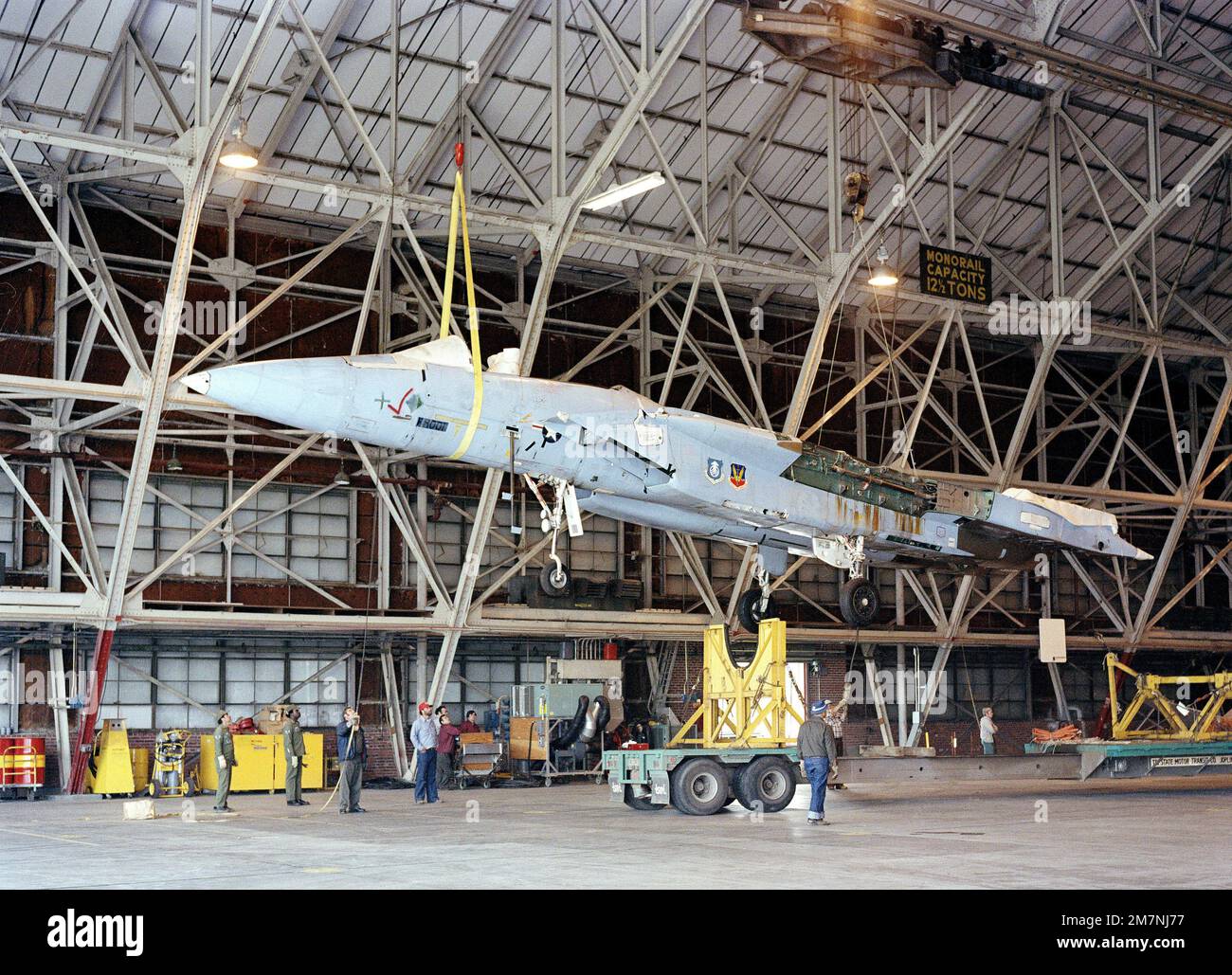 An F-15 Eagle aircraft fuselage is offloaded from a flatbed truck in ...