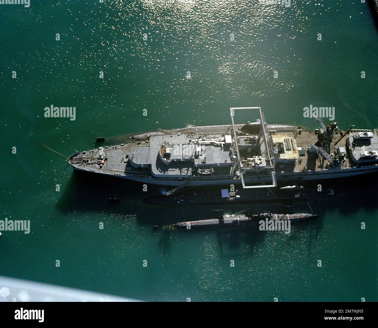 An aerial port view of the submarine tender USS PROTEUS (AS 19) with ...