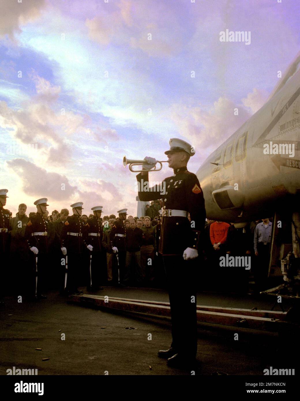 A U.S. Marine plays taps during a memorial service on the flight deck ...