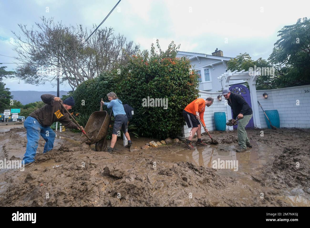 People shovel mud from the front of a home near Highway 101 in ...