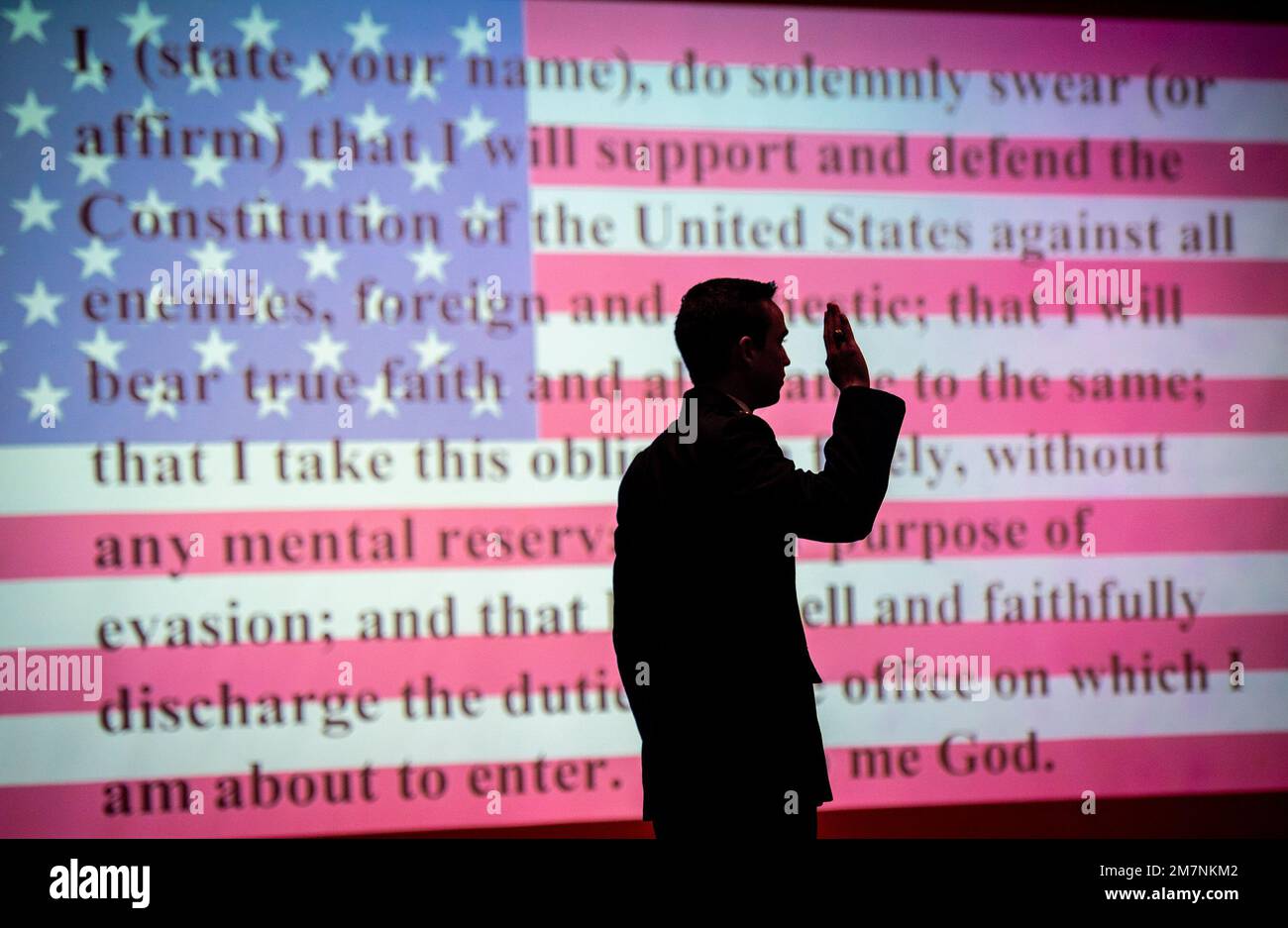 The Oath of Office is projected on a screen behind an ROTC cadet as he ...