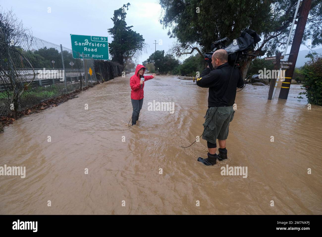 Members of media stand in the flooded area near Highway 101 in ...