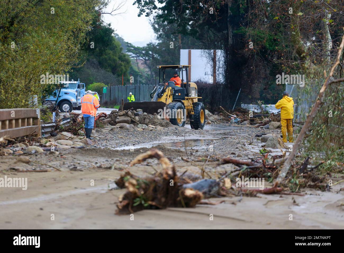 A work crew cleans up an area of Highway 101 that flooded in Montecito ...