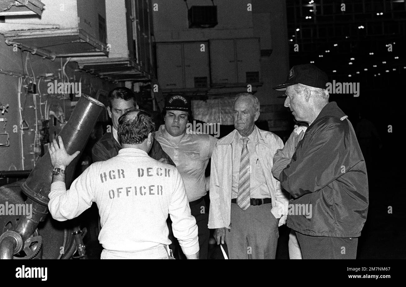 A hangar deck officer gives retired ADM David L. McDonald, with tie ...