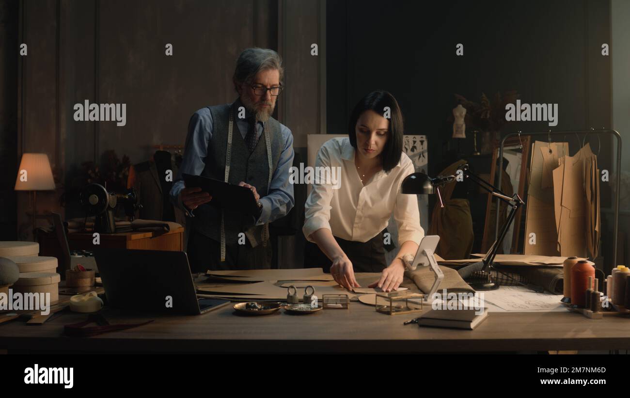 Tailor shows sketch of future clothes collection to seamstress on ...