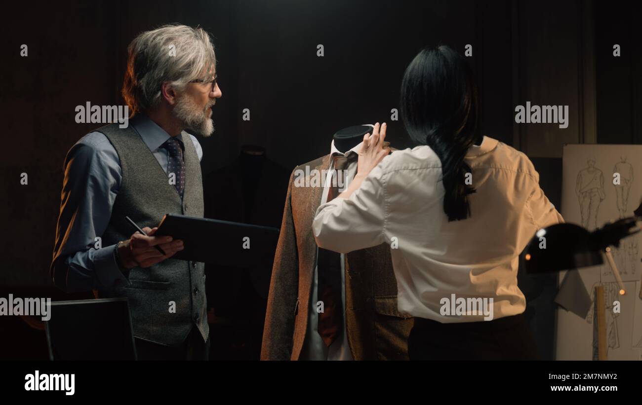 Male and female tailors work on business or wedding suit. Man draws ...