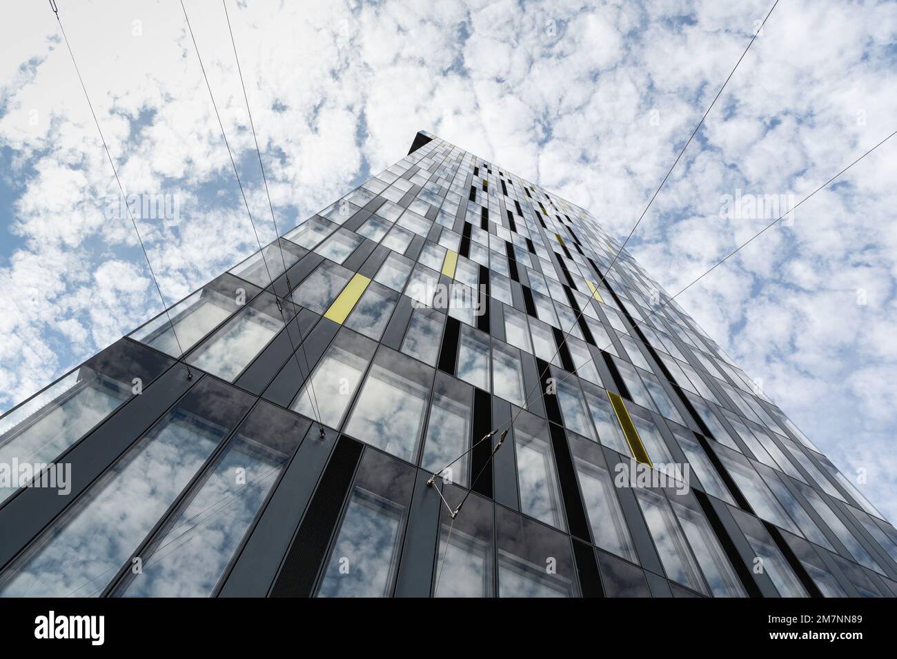 Blue sky and white clouds are reflected in the windows of a skyscraper ...