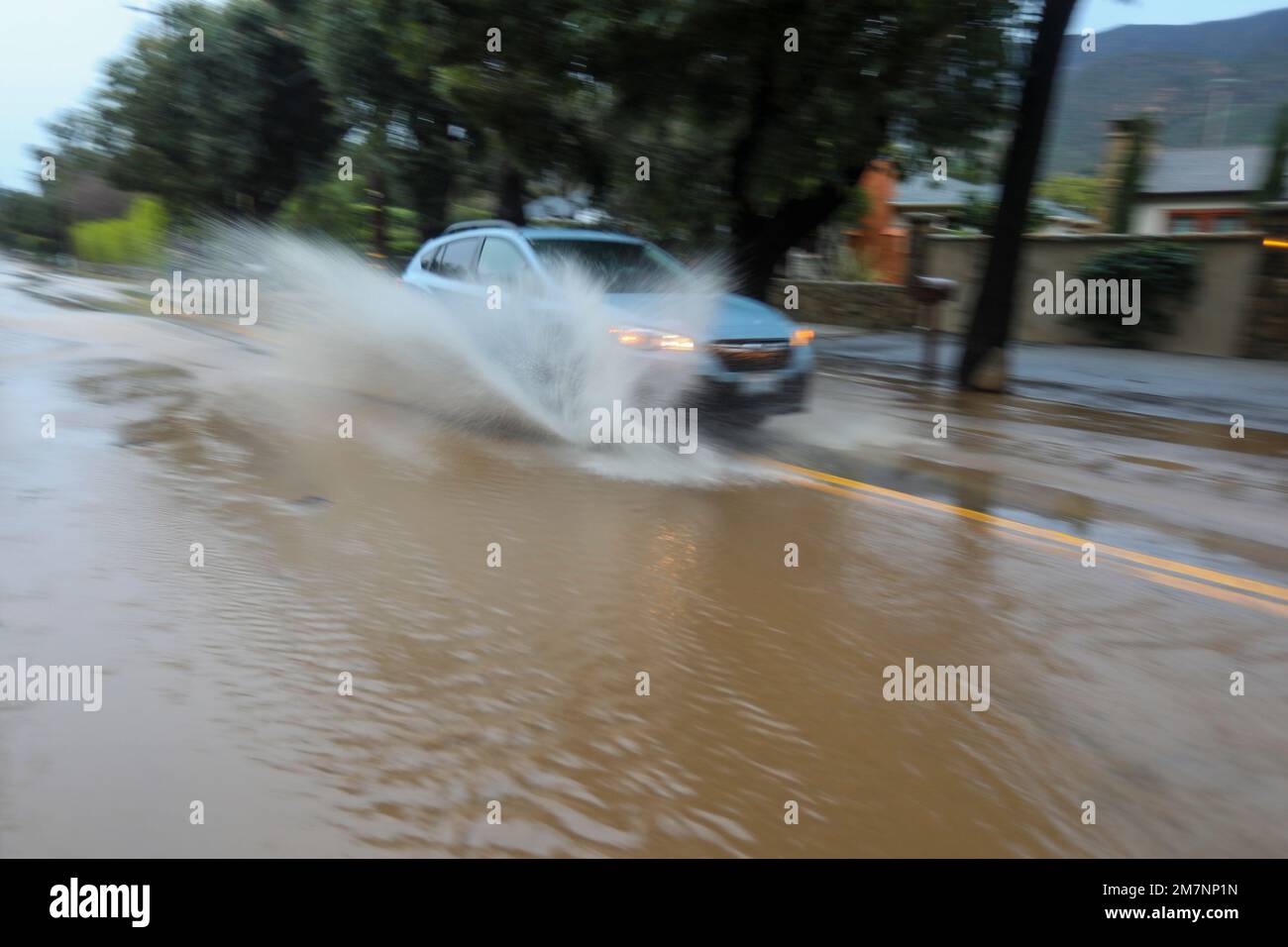 A vehicle drives through a flooded section of Highway 192 in Montecito ...