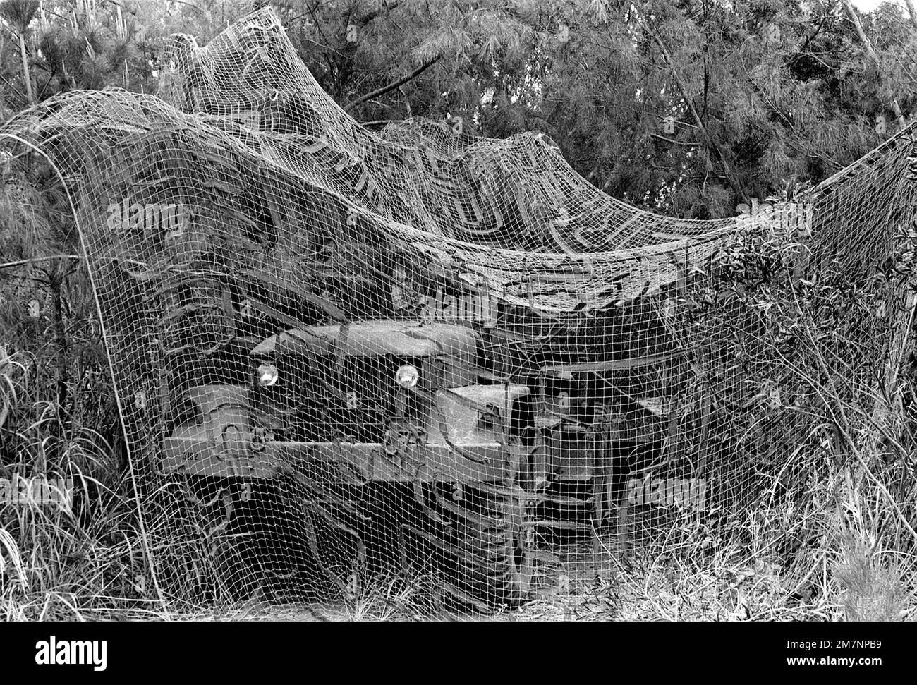 An M-48 tractor attached to a flatbed trailer is covered with a large ...