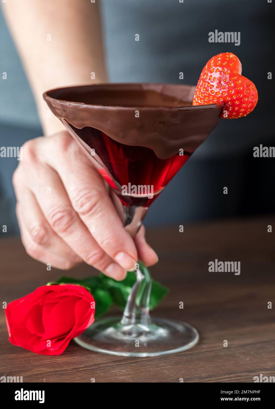 A hand holding a chocolate rimmed Valentine's Day cocktail in a martini ...